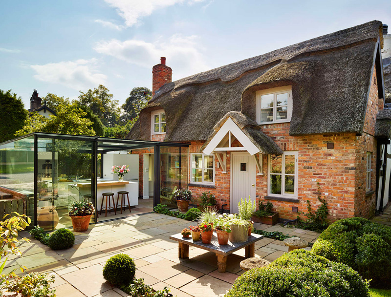 This thatched cottage got a glass box extension for the kitchen