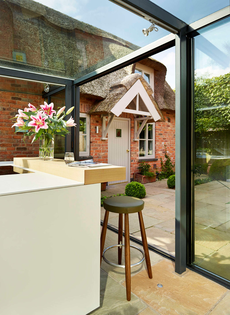 This thatched cottage got a glass box extension for the kitchen