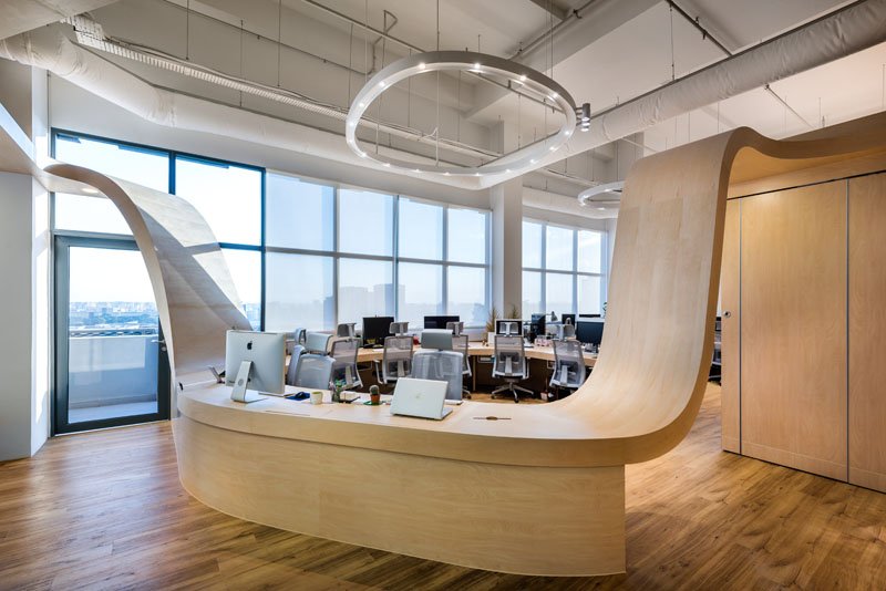 A ribbon-like wood table winds its way throughout this office, and the ...