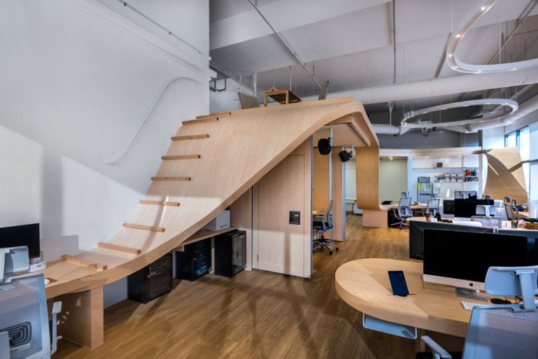 A ribbon-like wood table winds its way throughout this office, and the ...