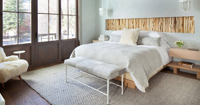 A recessed wall section filled with rustic branches acts as a headboard ...