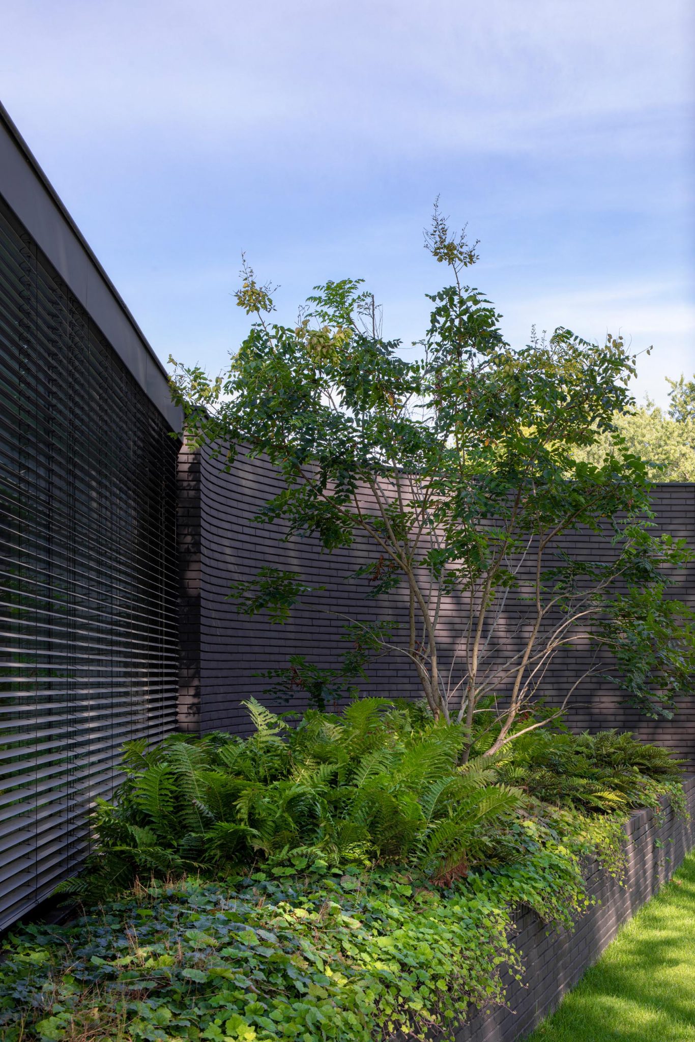 This Home Combines A Black Brick Exterior With Large Glass Walls For A ...