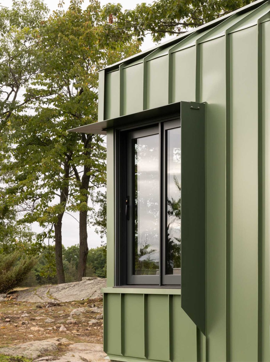 Green Metal Siding Allows This Small Cottage To Blend In With Its Surroundings